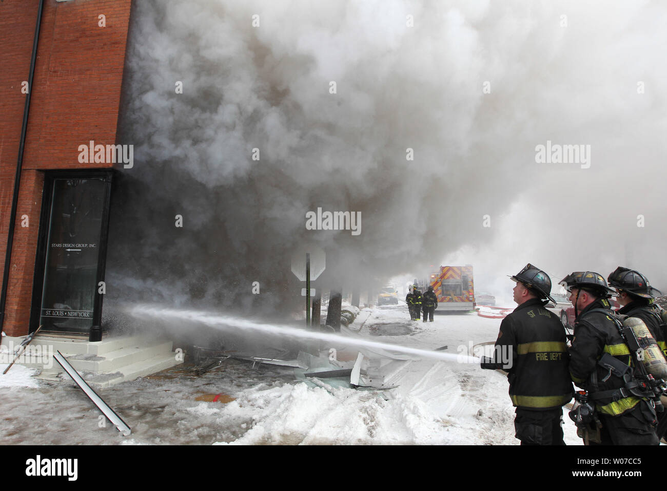 St. Louis firefighters advance a hose line as fire erupts from inside a ...