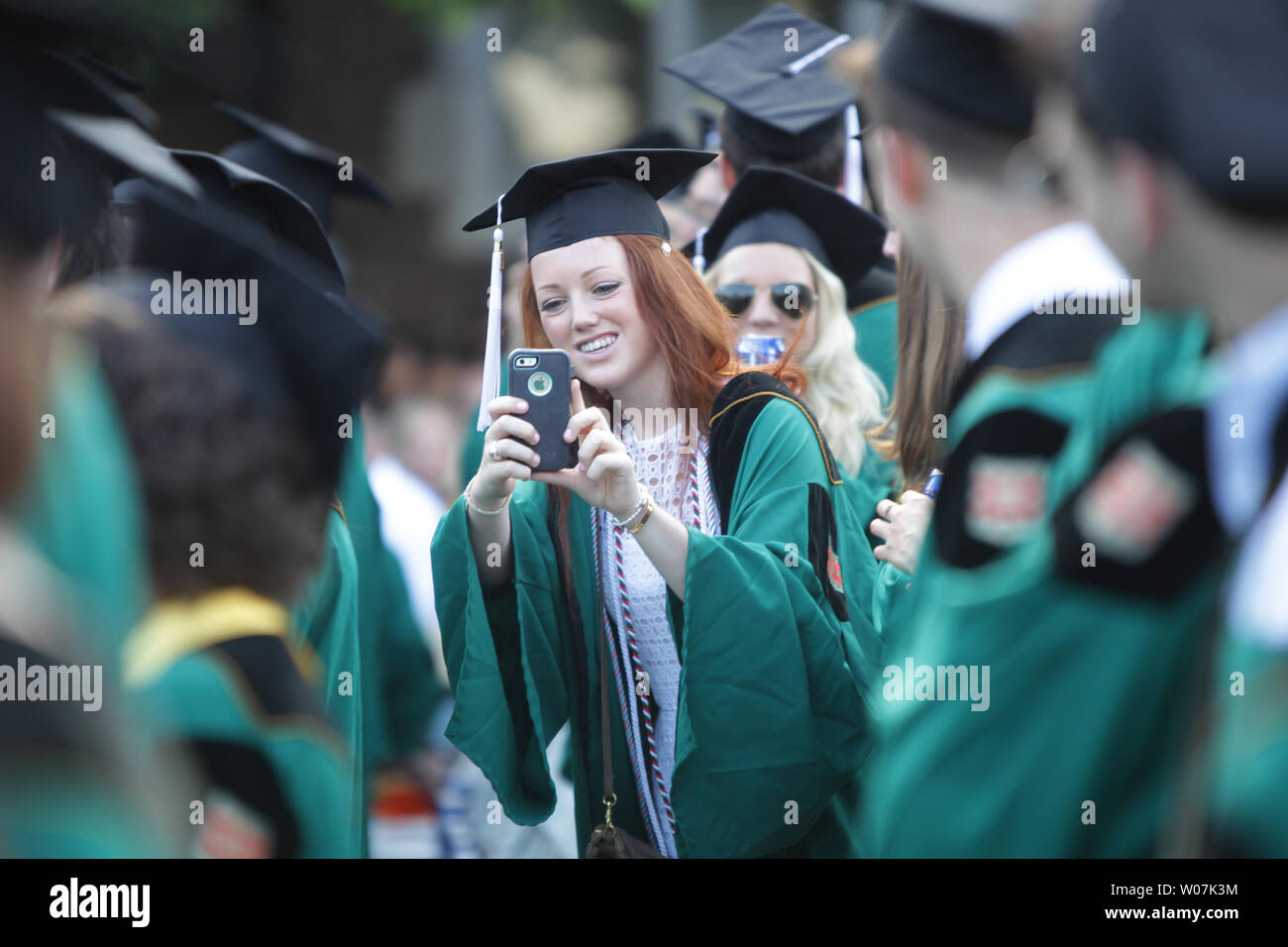 A graduating senior uses a cell phone to make a photo of classmates ...