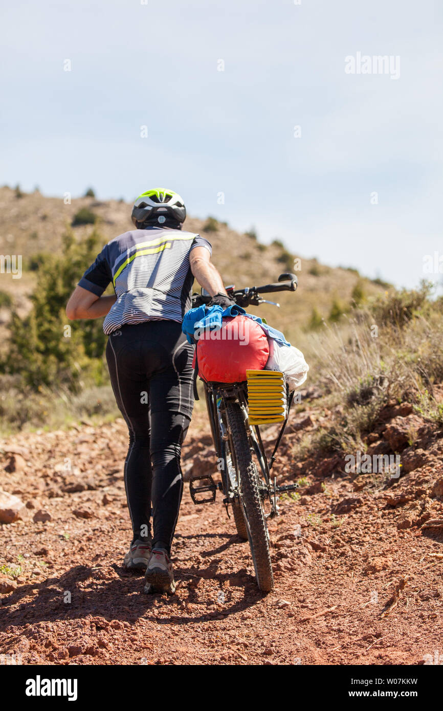 Man cyclist pushing his touring bike over the hills along the G10 long ...