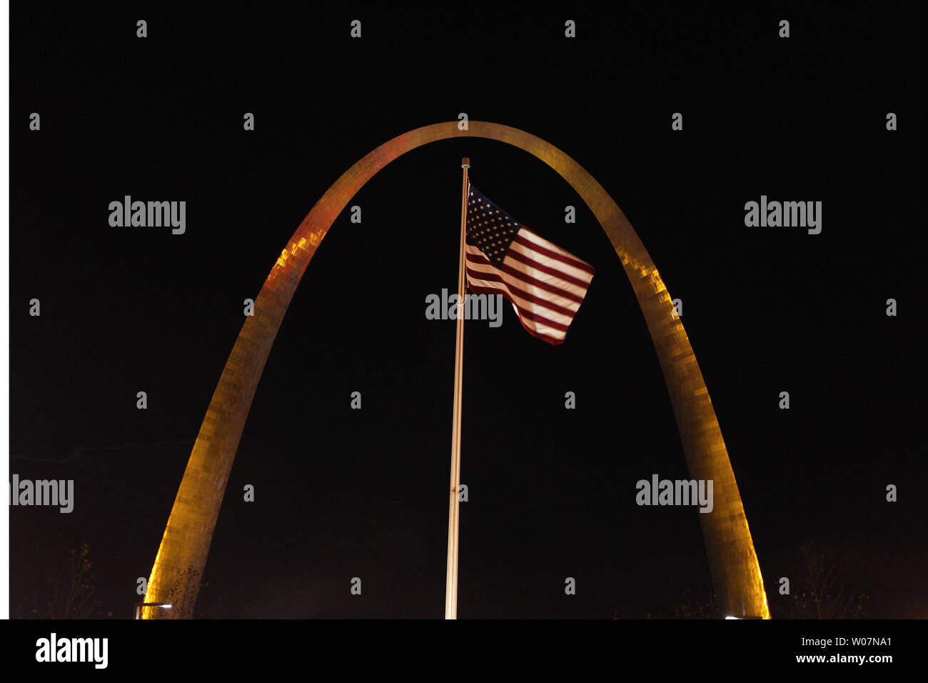 An American flag flies in the foreground as the 630 foot Gateway Arch ...
