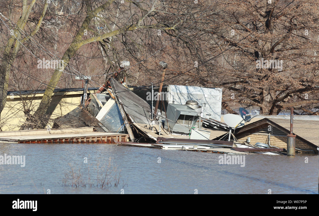 Building debris become wedged against a flooded home as water from the ...
