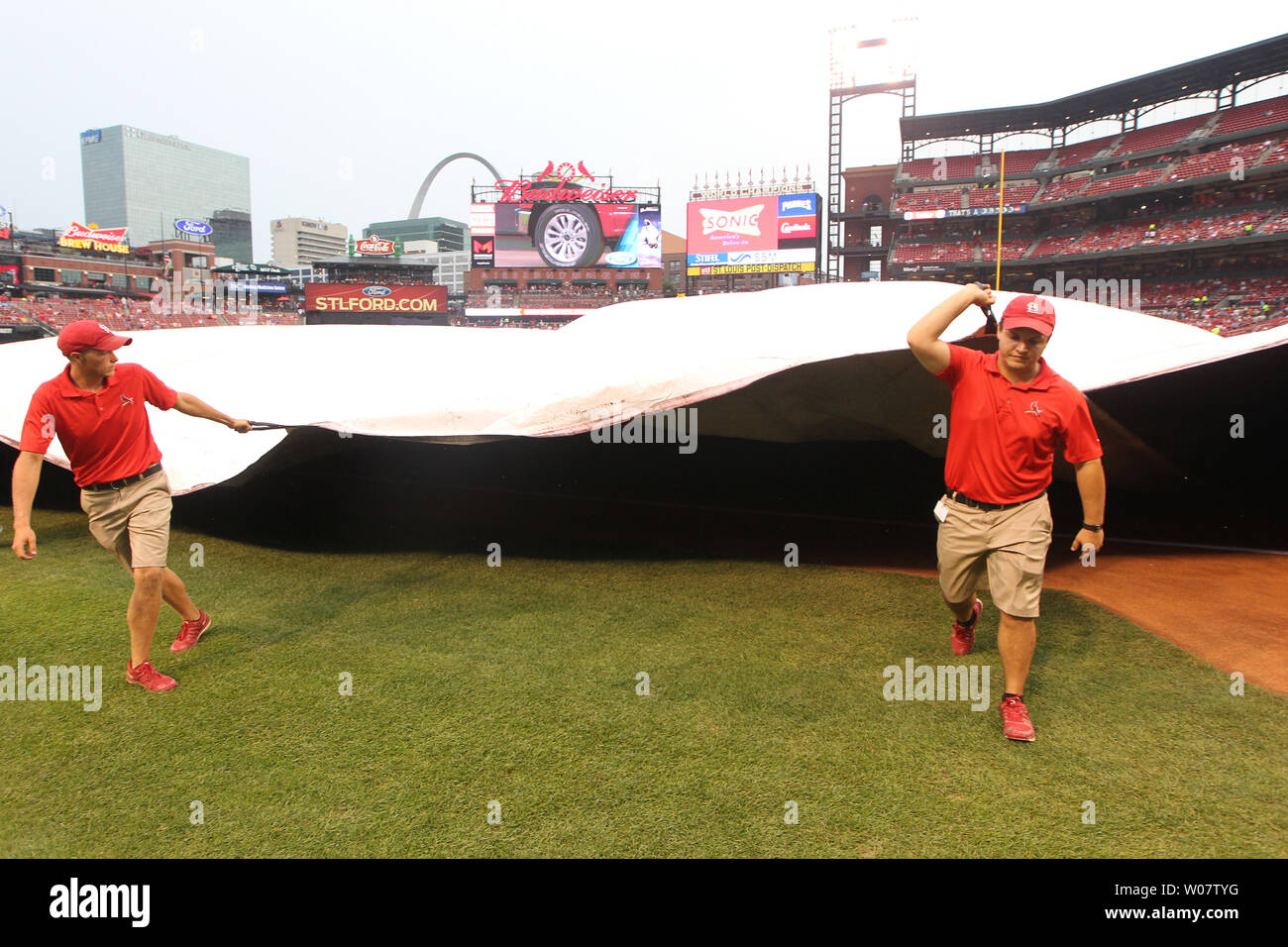 Busch Stadium grounds crew members place the tarp on the infield, as ...