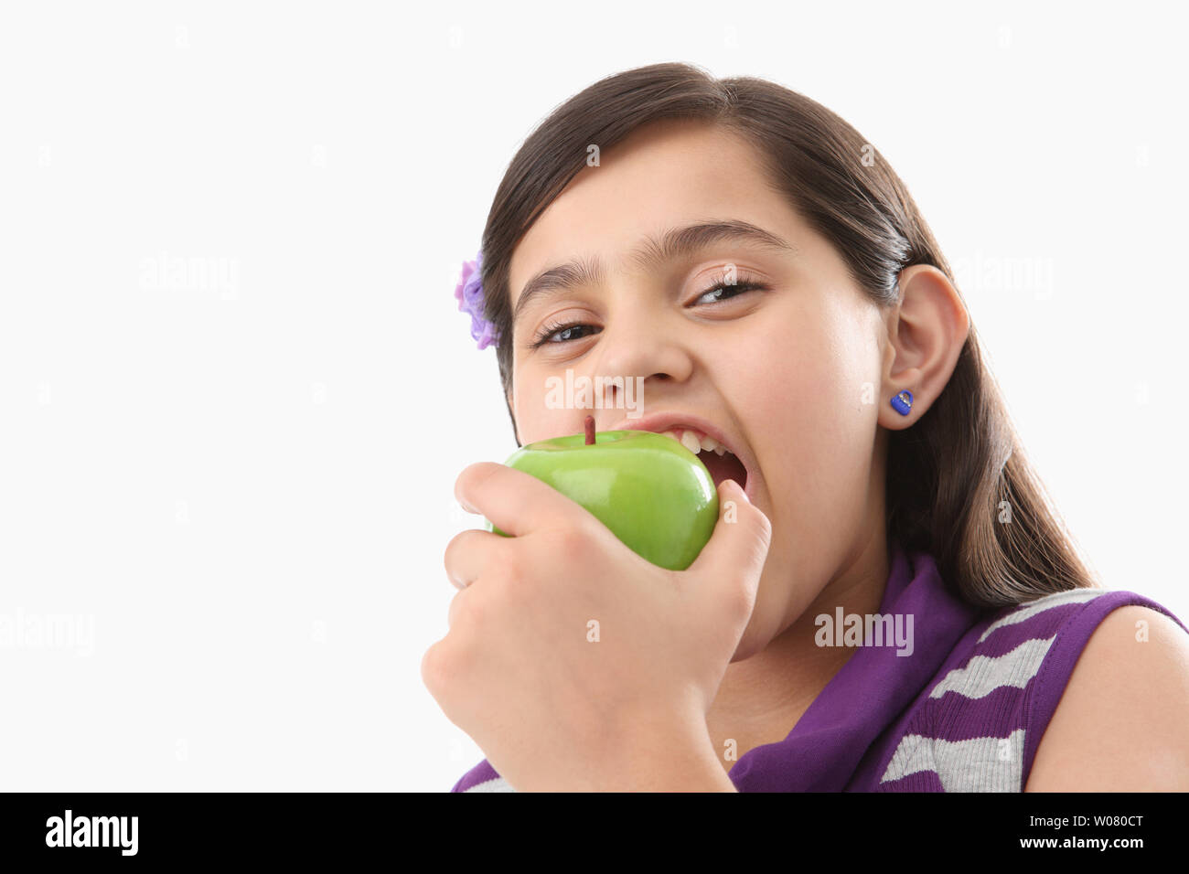 Indian girl eating a green apple Stock Photo - Alamy