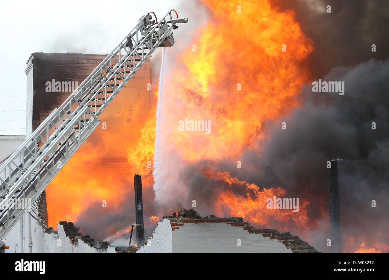 A fire rages out of control in a warehouse after walls collapsed during ...