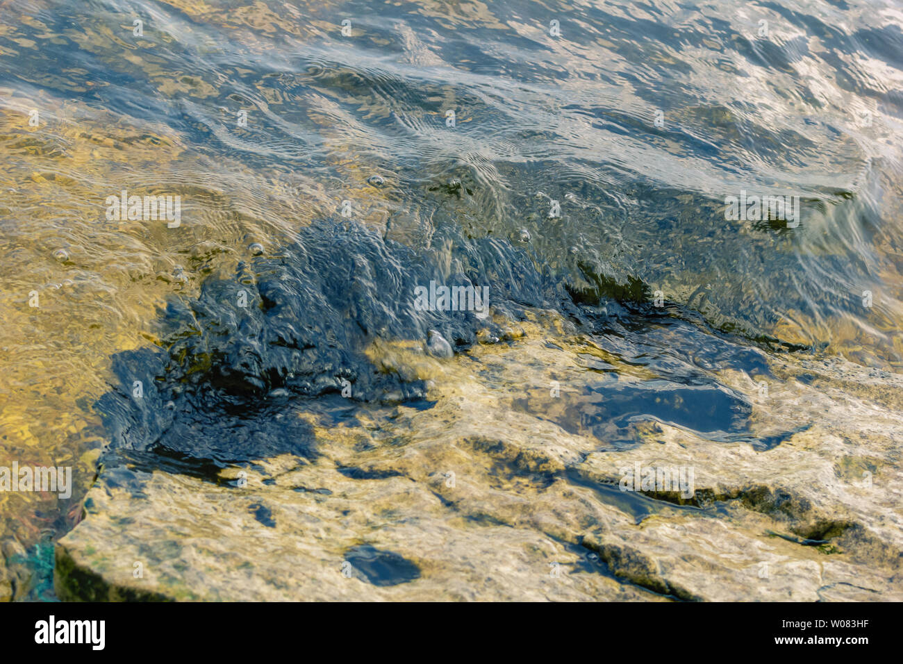 Natural liquid texture. River wave runs on the rocky shore Stock Photo ...
