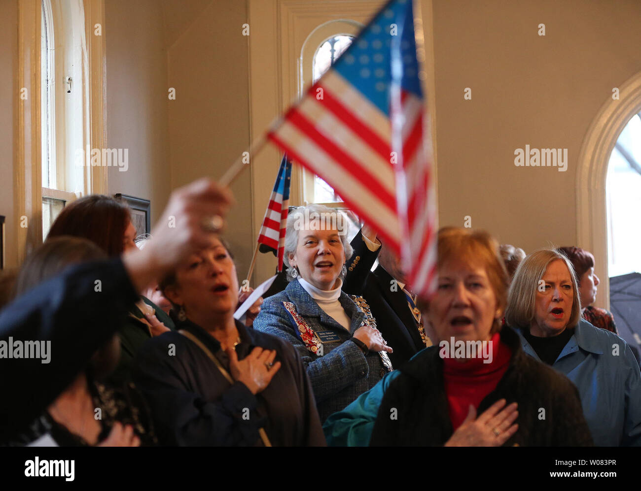 An American flag is held while people sing the National Anthem before ...