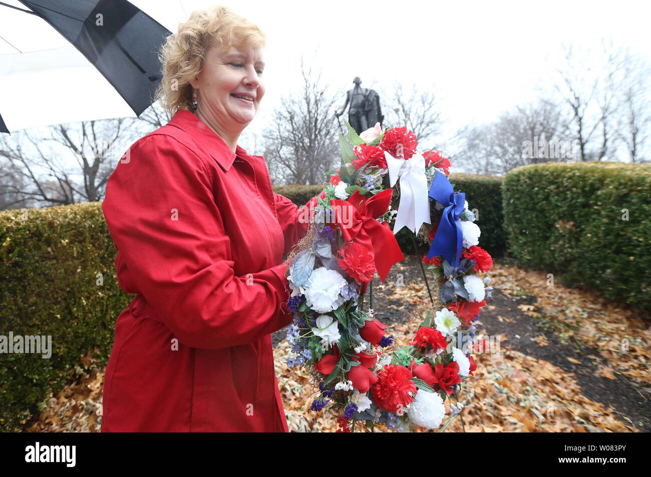 Rachel Wilhelm places a wreath of flowers at the base of a statue of ...
