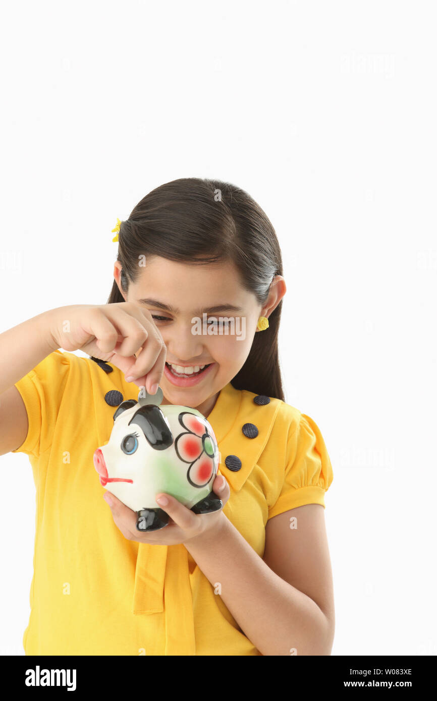 Indian girl inserting coin into a piggy bank and smiling Stock Photo ...