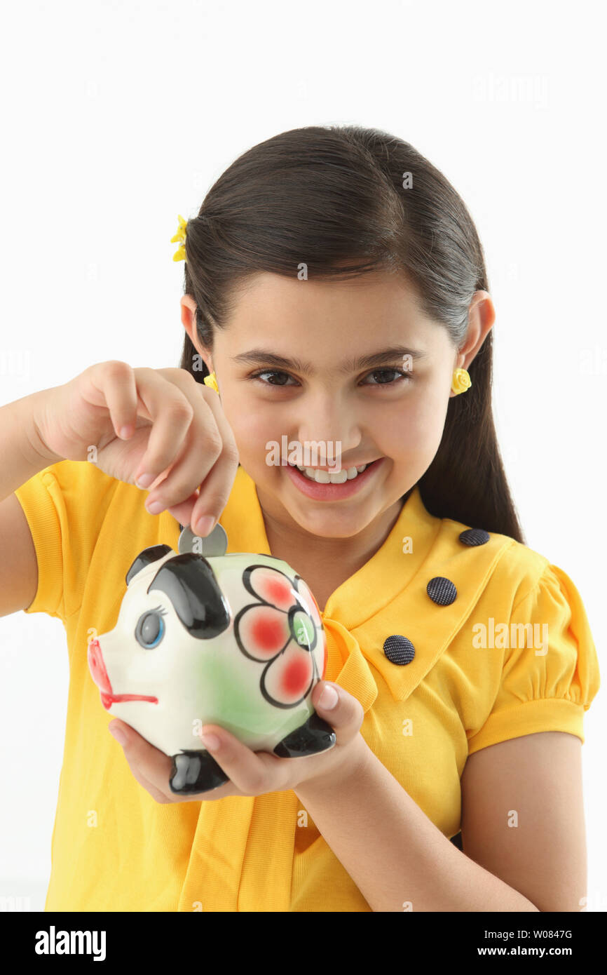 Indian girl inserting coin into a piggy bank and smiling Stock Photo ...