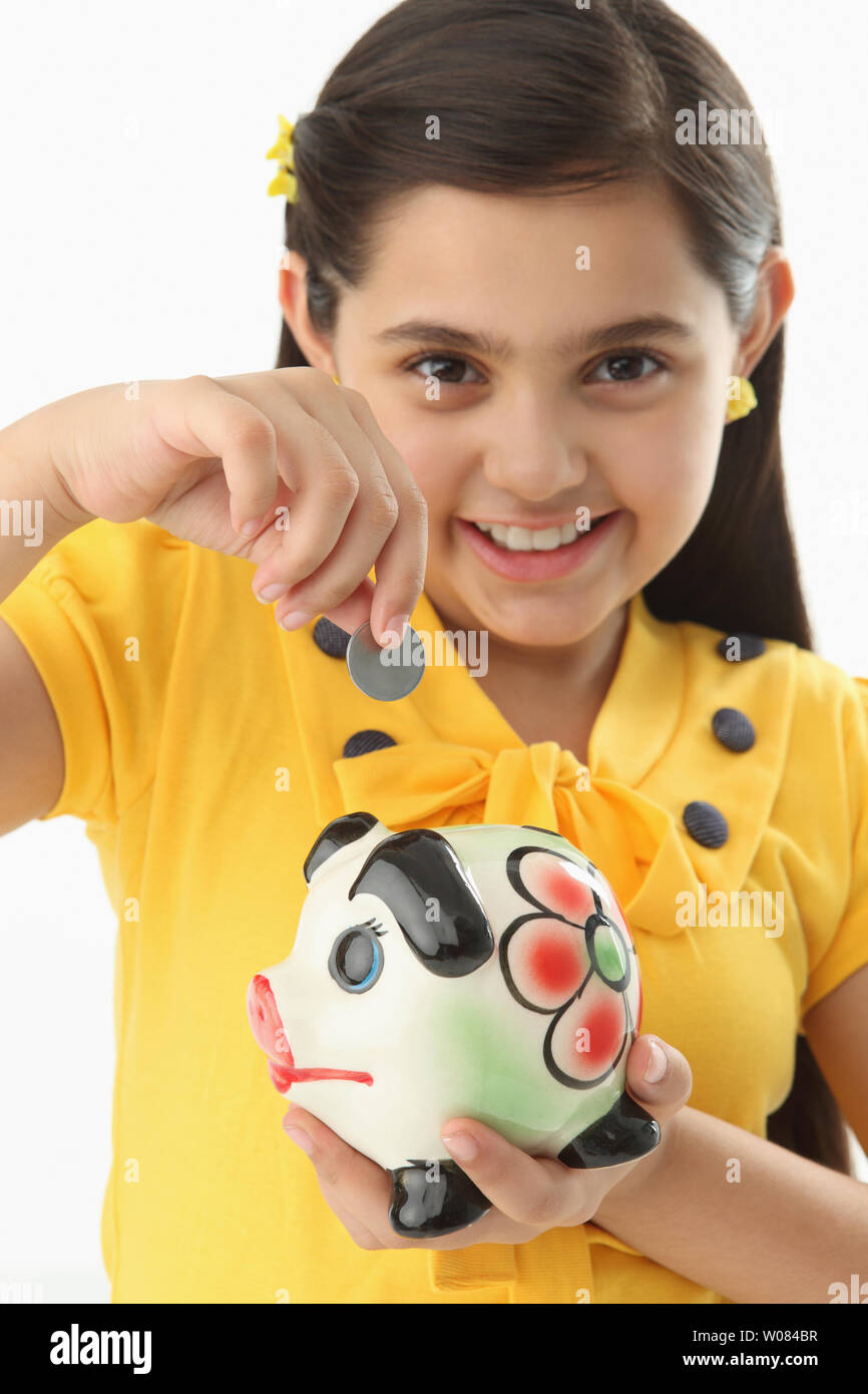 Indian girl inserting coin into a piggy bank and smiling Stock Photo ...
