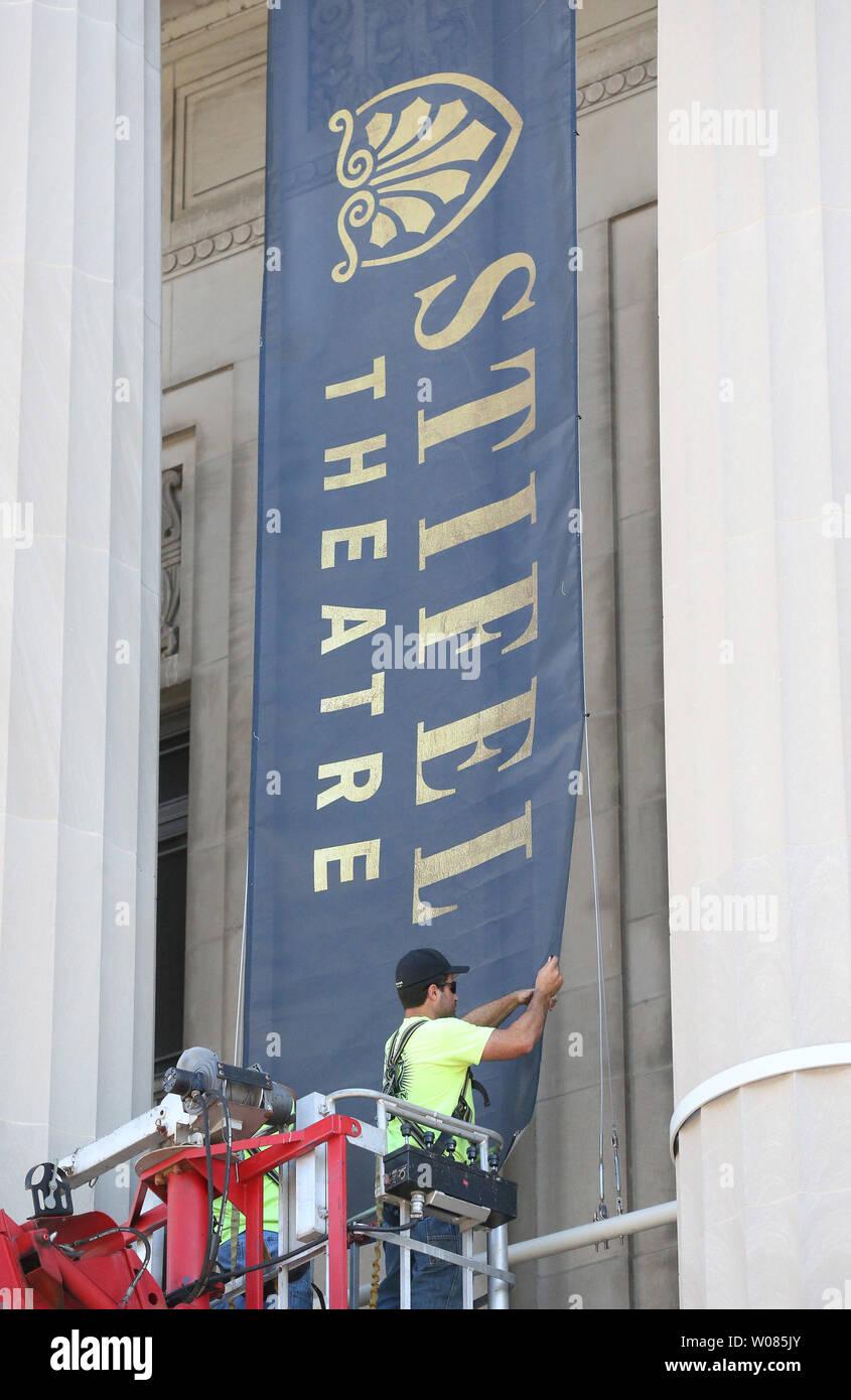 A worker from Warren Sign Company secures a banner following ceremonies ...