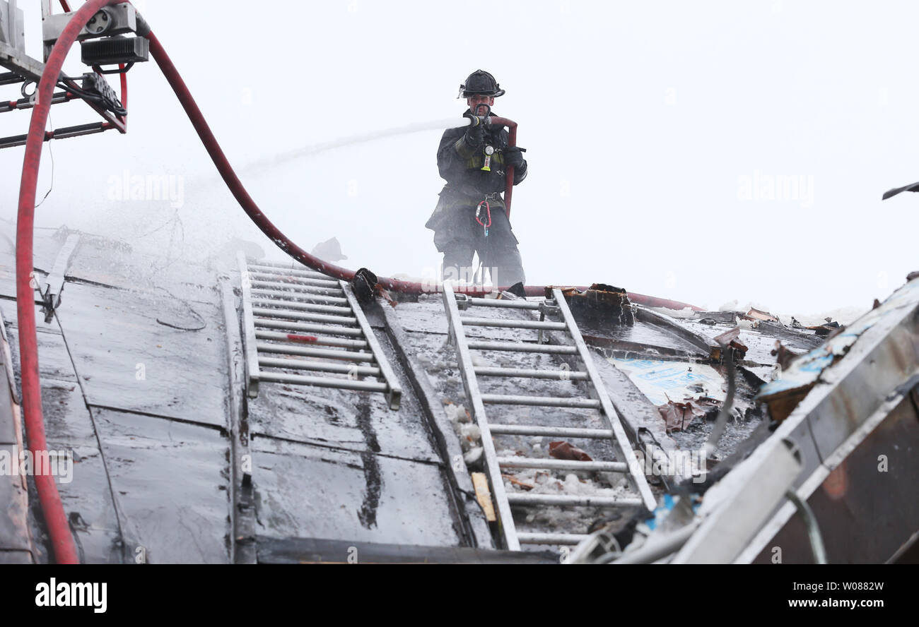 A St. Louis firefighter uses a hose to cool down hot spots on a cooper ...