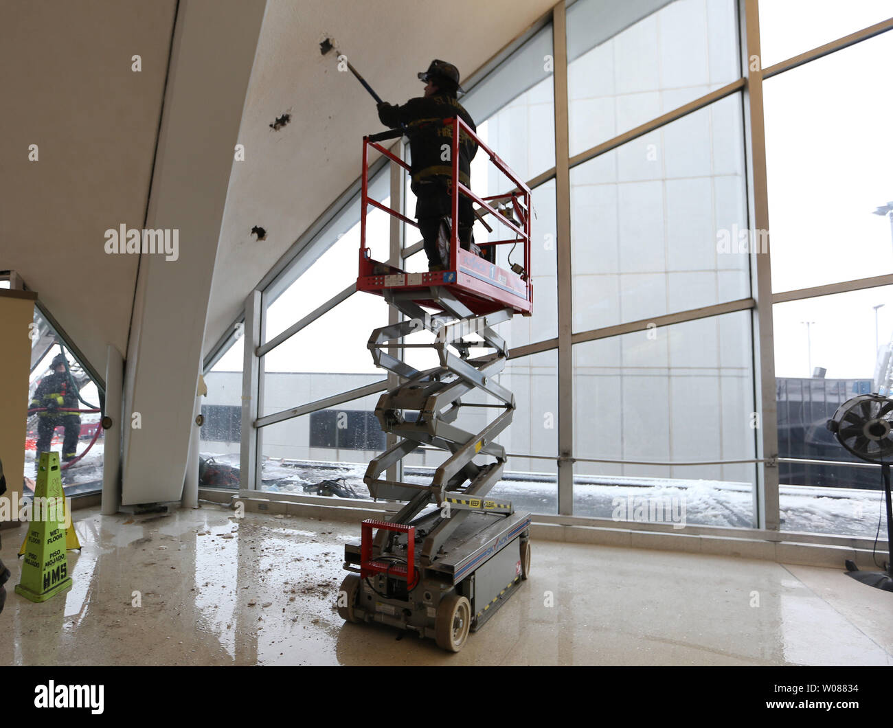 A St. Louis firefighter uses a pike pole to look for hot spots in the ...