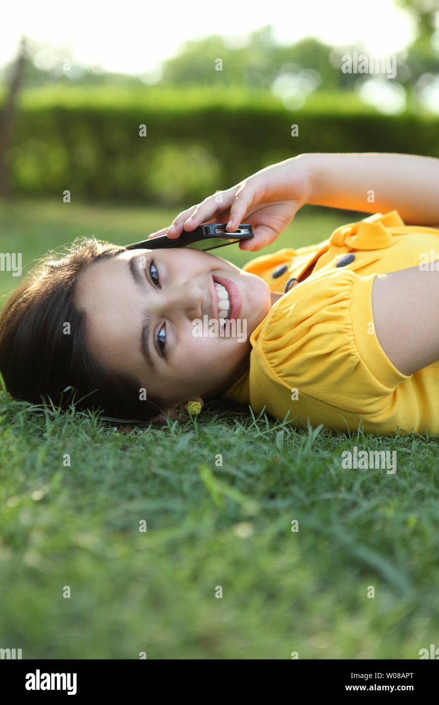 Indian girl talking on a mobile phone in a park Stock Photo - Alamy