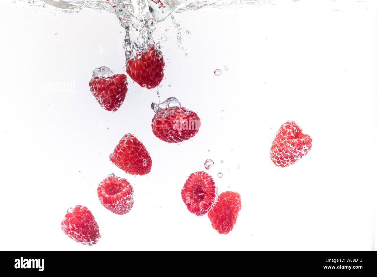 Raspberries splashing into crystal clear water with air bubbles Stock ...