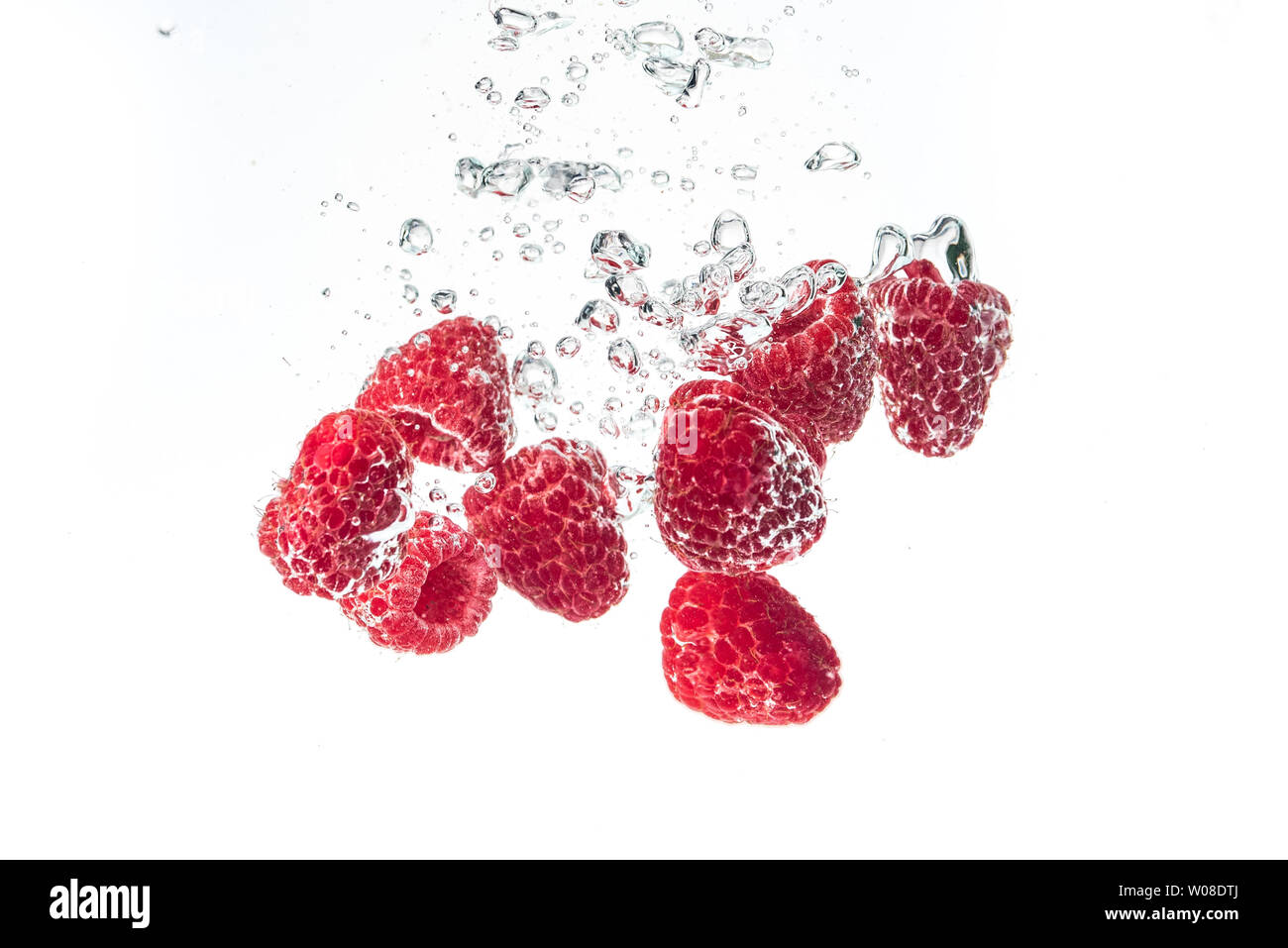Raspberries splashing into crystal clear water with air bubbles Stock ...