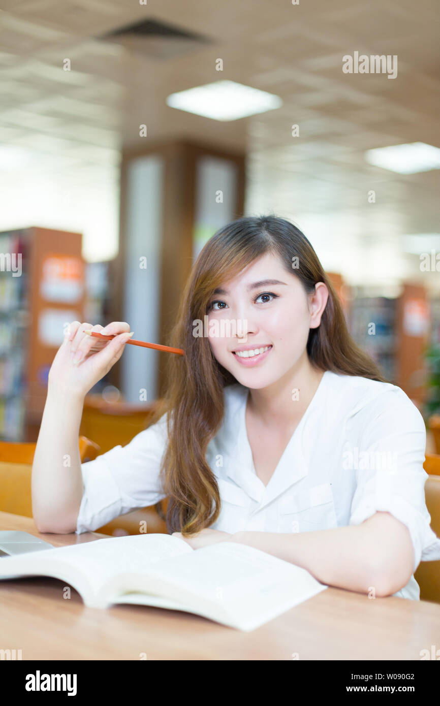 young beautiful asian girl university student with laptop in library ...