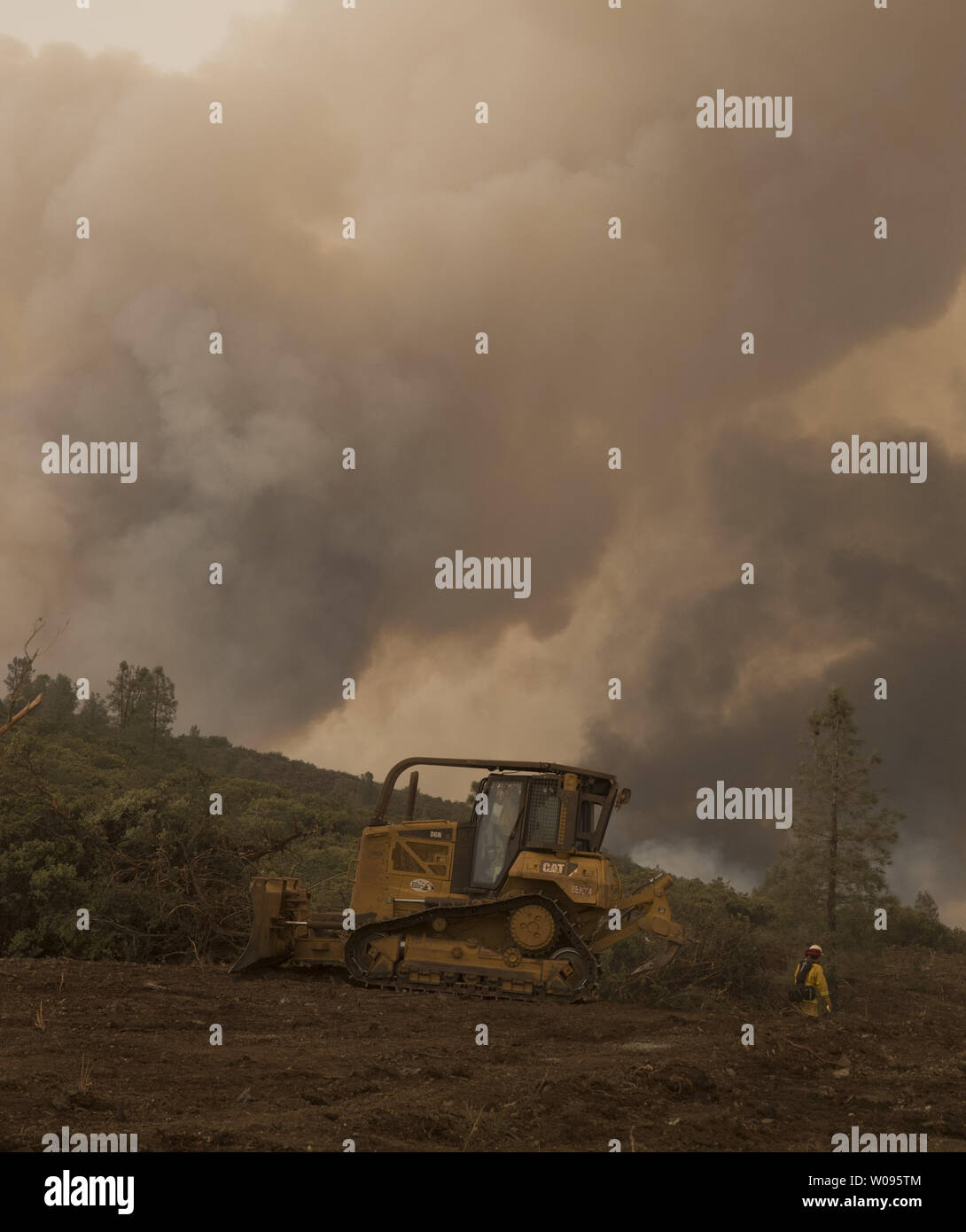 CalFire personnel use a bulldozer to create a fire break along a ridge ...