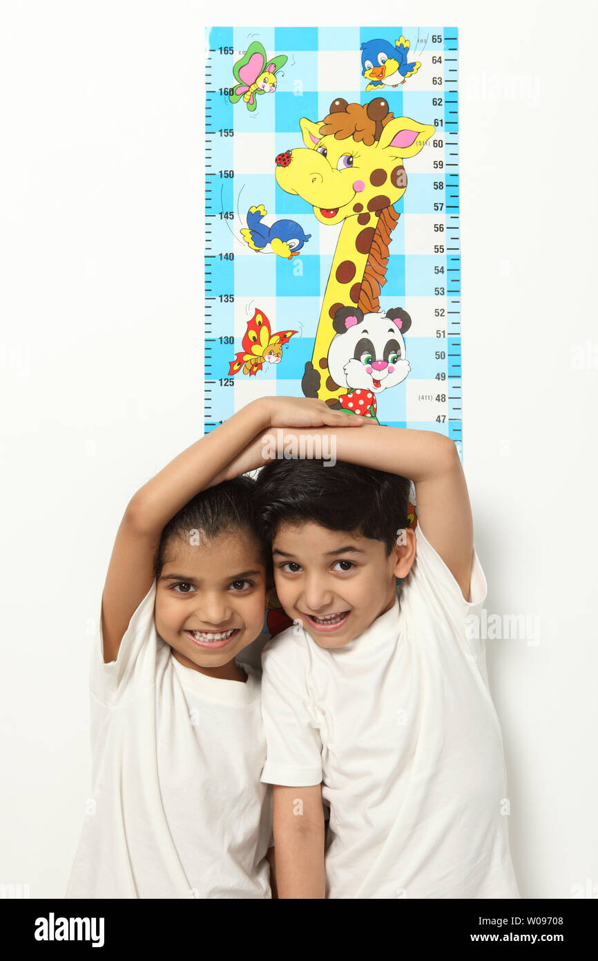 Portrait of two Indian children measuring their heights Stock Photo - Alamy