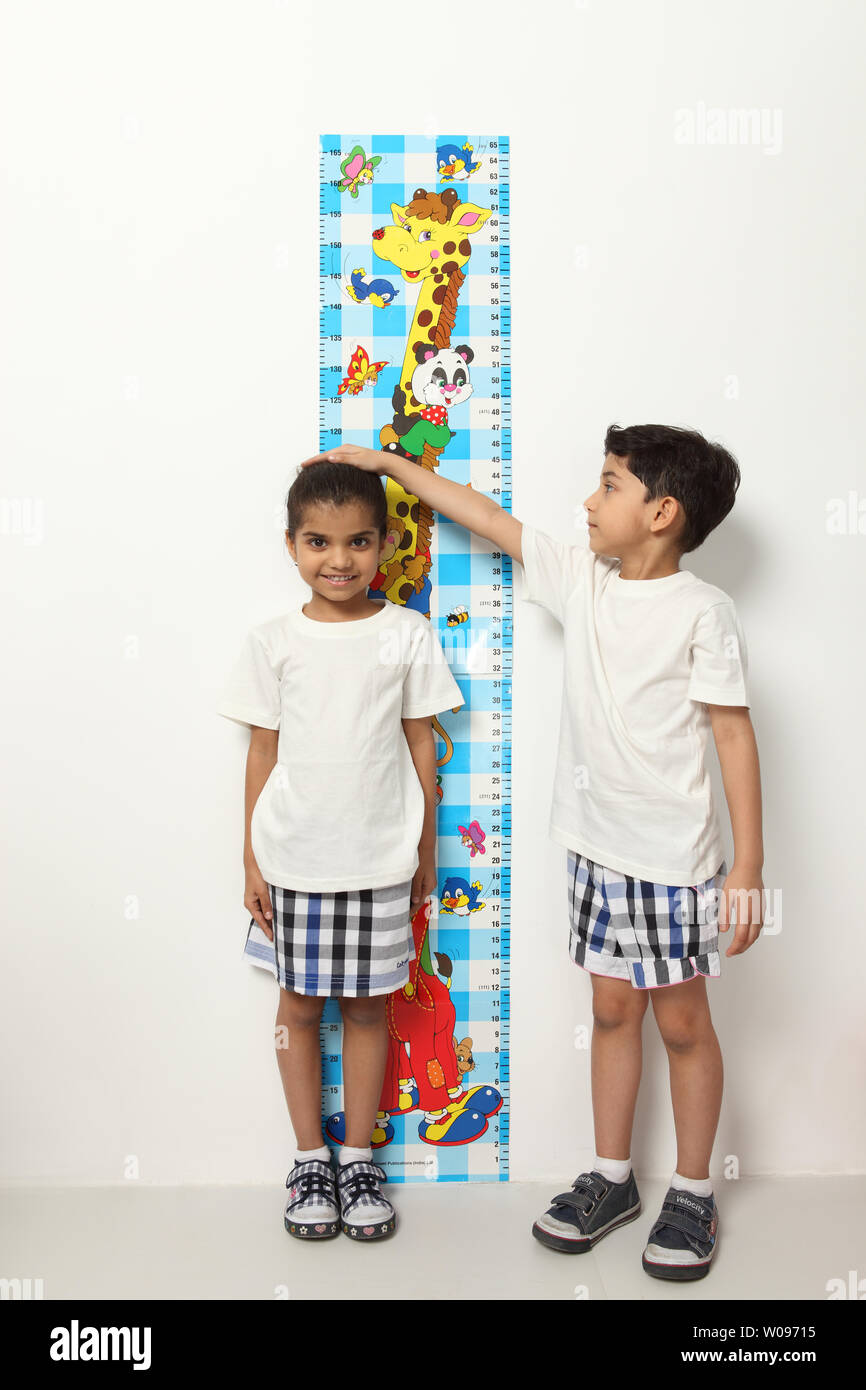 Boy measuring height of a girl Stock Photo - Alamy