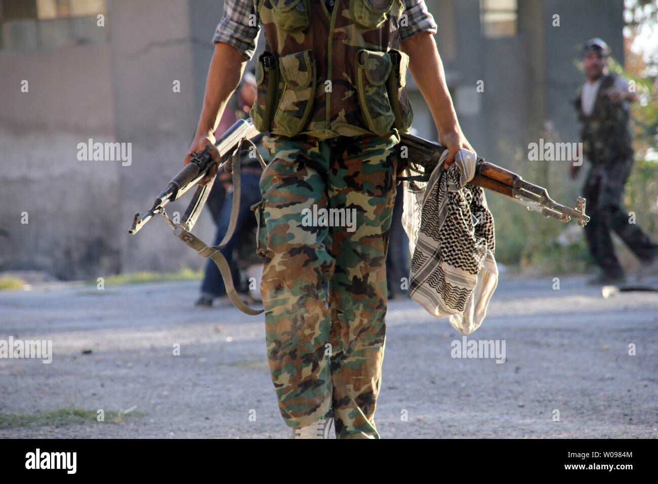 A member of the Free Syrian Army carries his weapon during fighting in ...