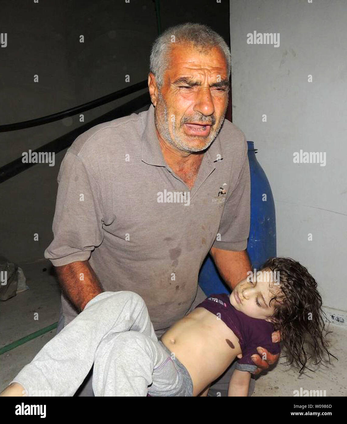 Syrian man carries the body of a dead child at a makeshift morgue as ...