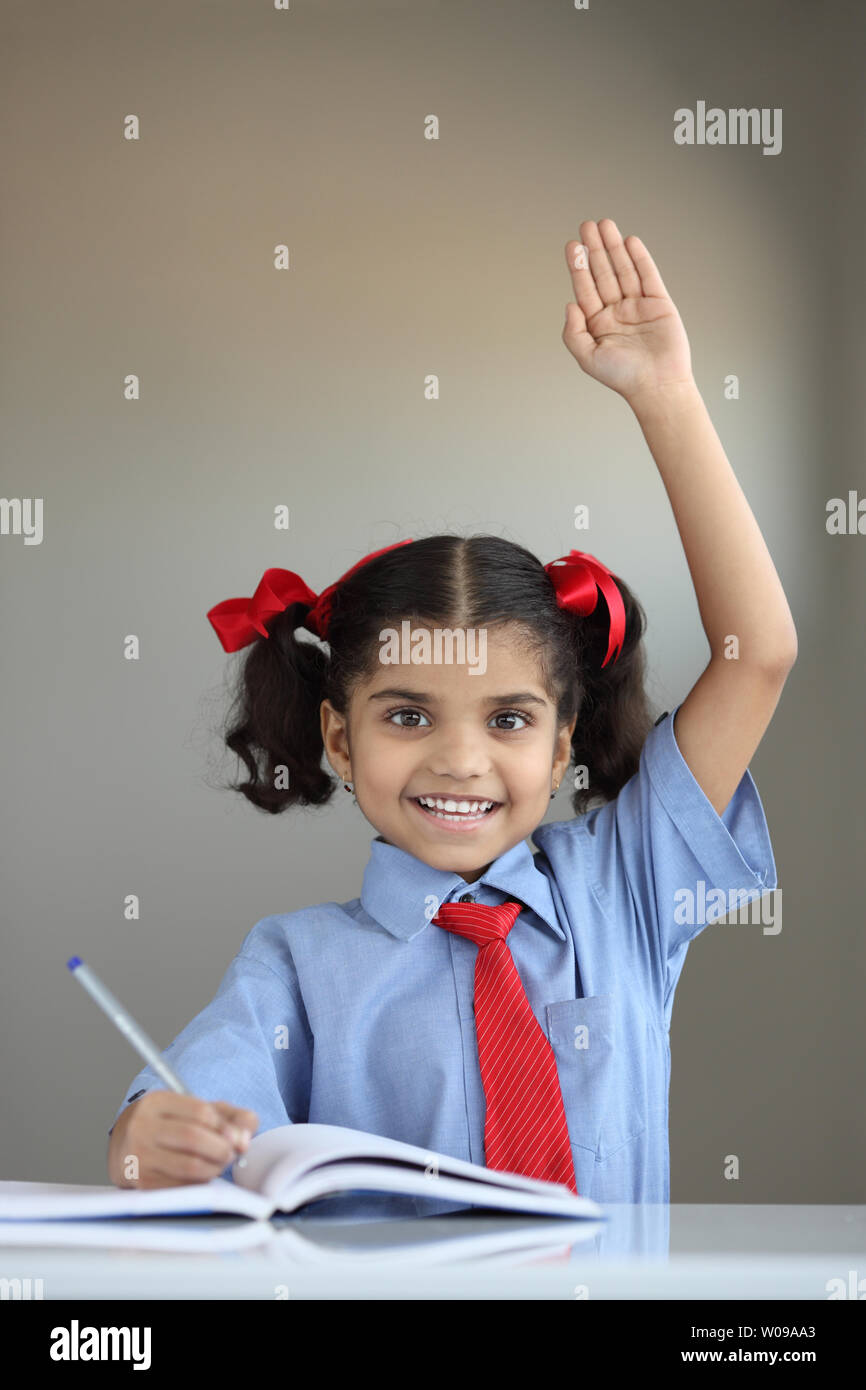 Portrait of a schoolgirl raising hand in classroom Stock Photo - Alamy