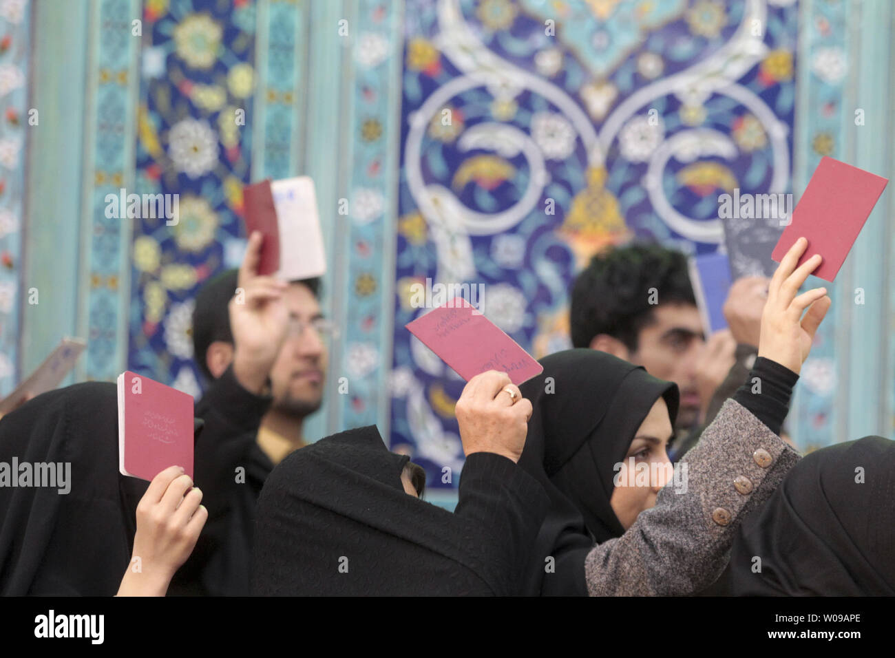 Iranian voters hold their identification cards at a polling station in ...