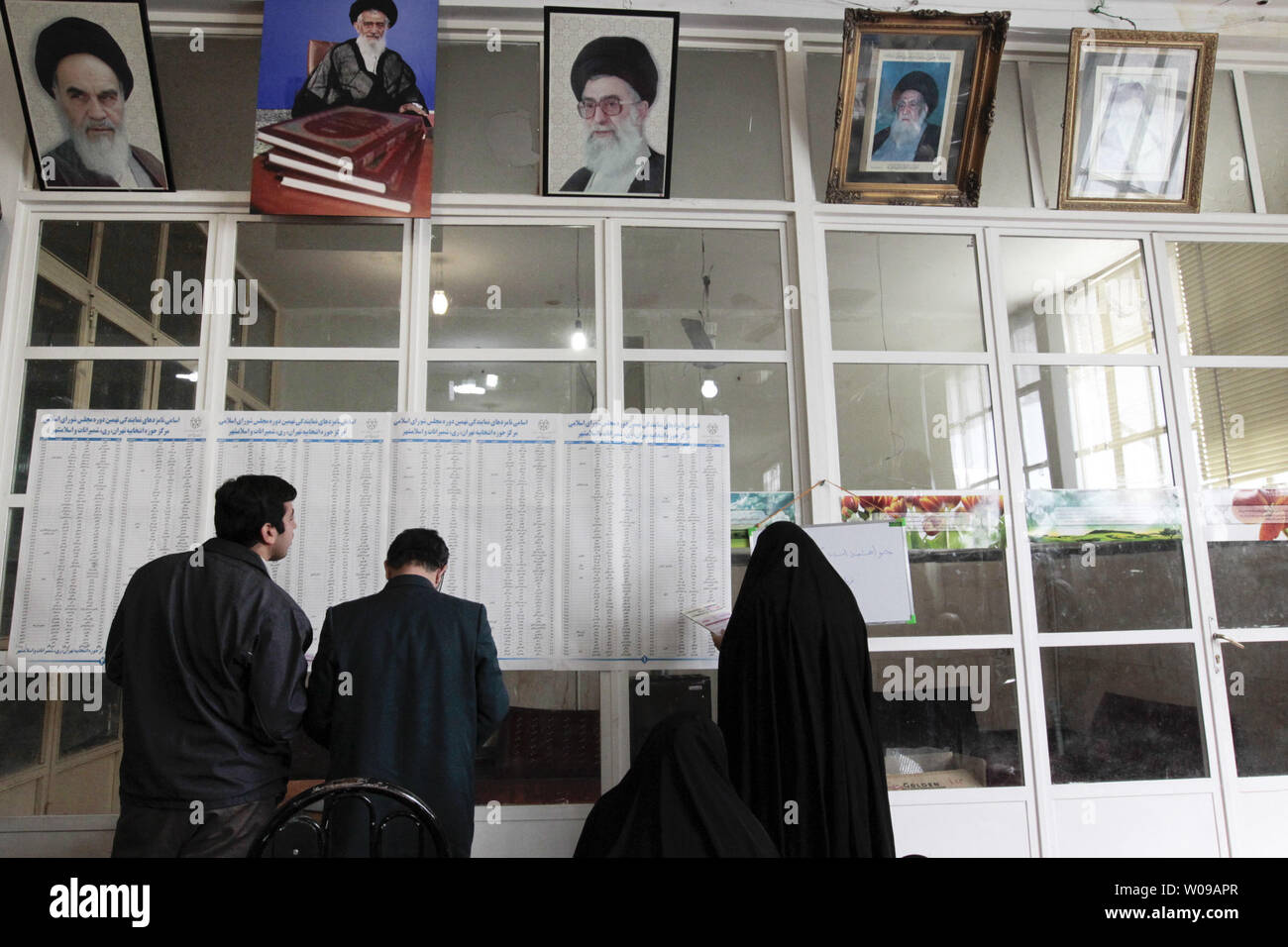 Iranians look at the candidates list and fill in their voting forms at ...