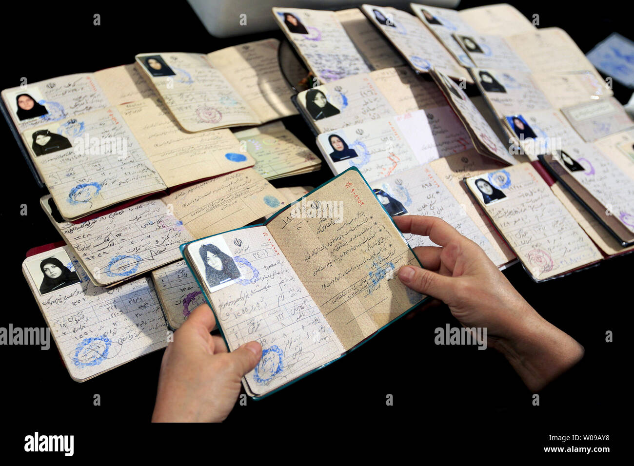 Staff look at the identification cards of Iranian voters at a polling ...