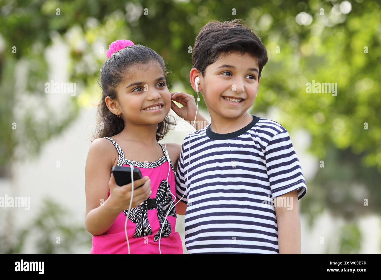 Two children listening to an Mp3 player Stock Photo - Alamy