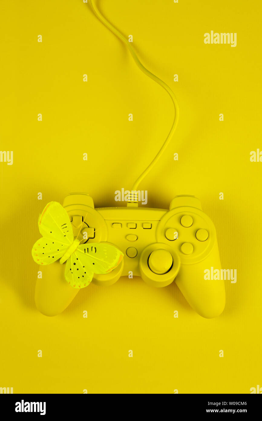 a yellow painted video game controller and a yellow butterfly on it on ...