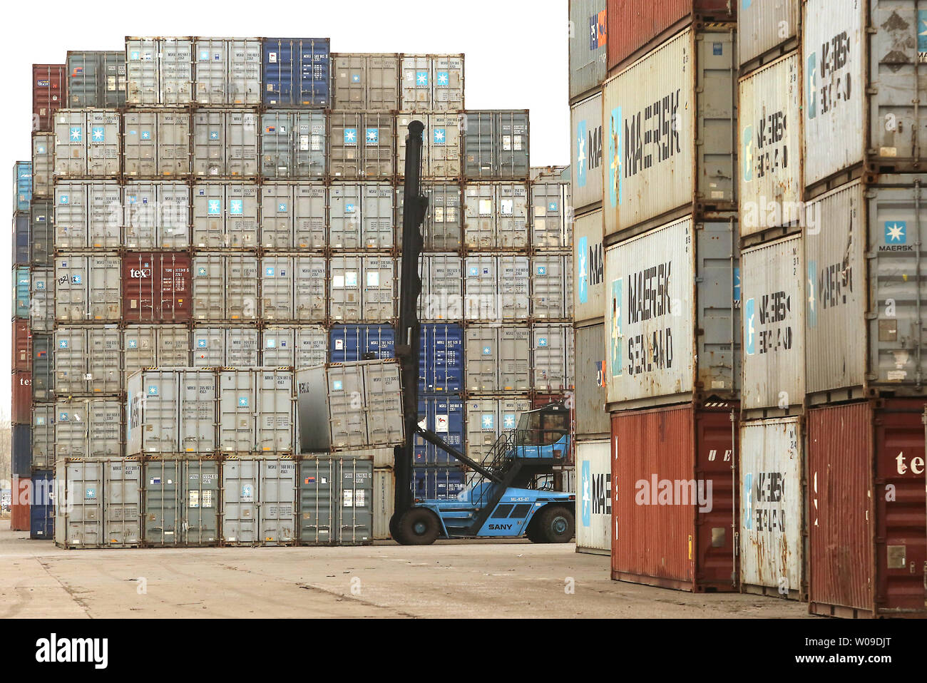 A shipping container lift crane delivers a container to a storage site ...