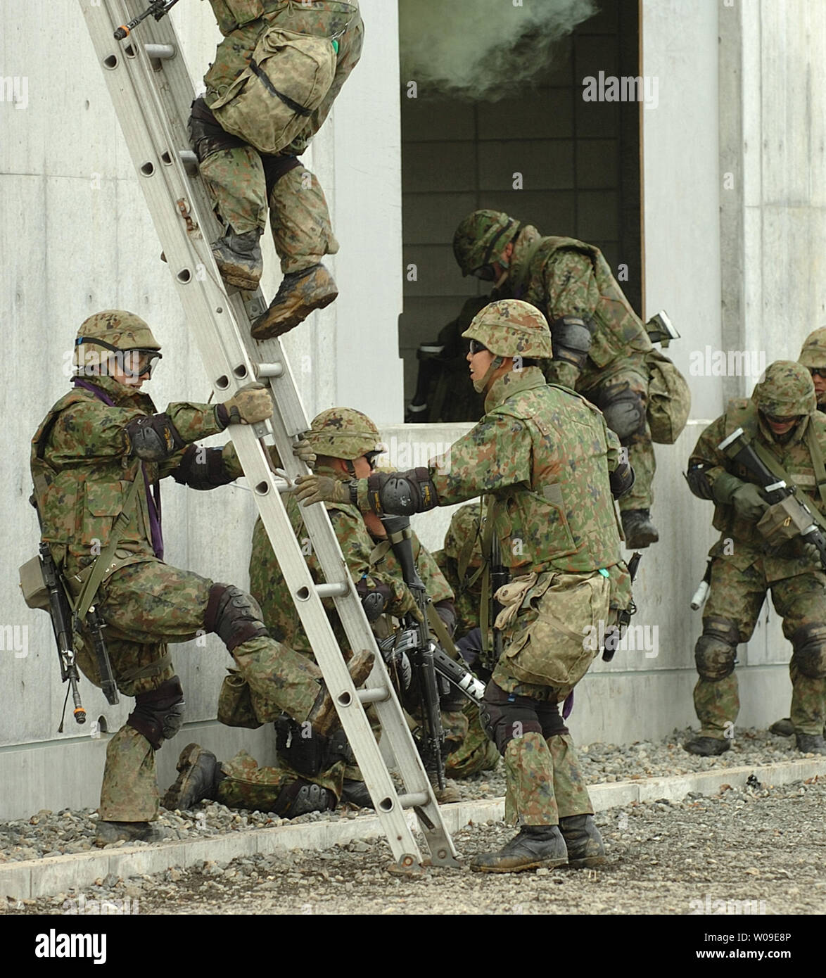 Japan's Ground Self-Defense Force personnel dash into a building during ...