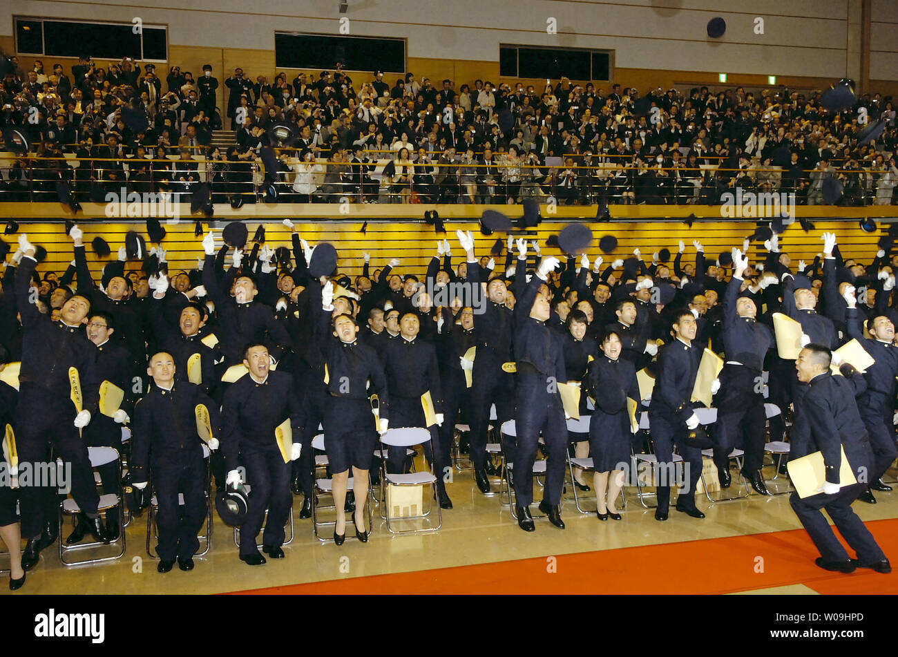 Japan's National Defense Academy graduates throw their caps in the air ...