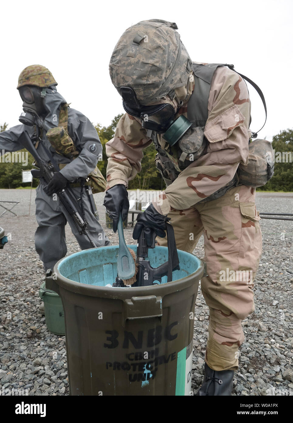 Member of U.S. Army conduct a decontamination for his M4 carbine during ...