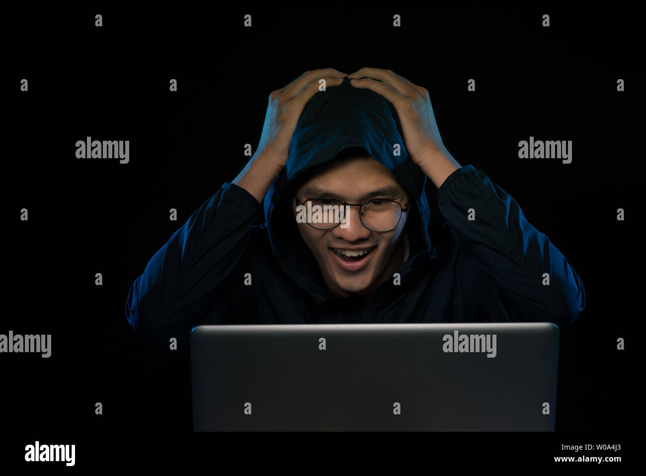 Successful male hacker poses in front of laptop computer, clenches ...