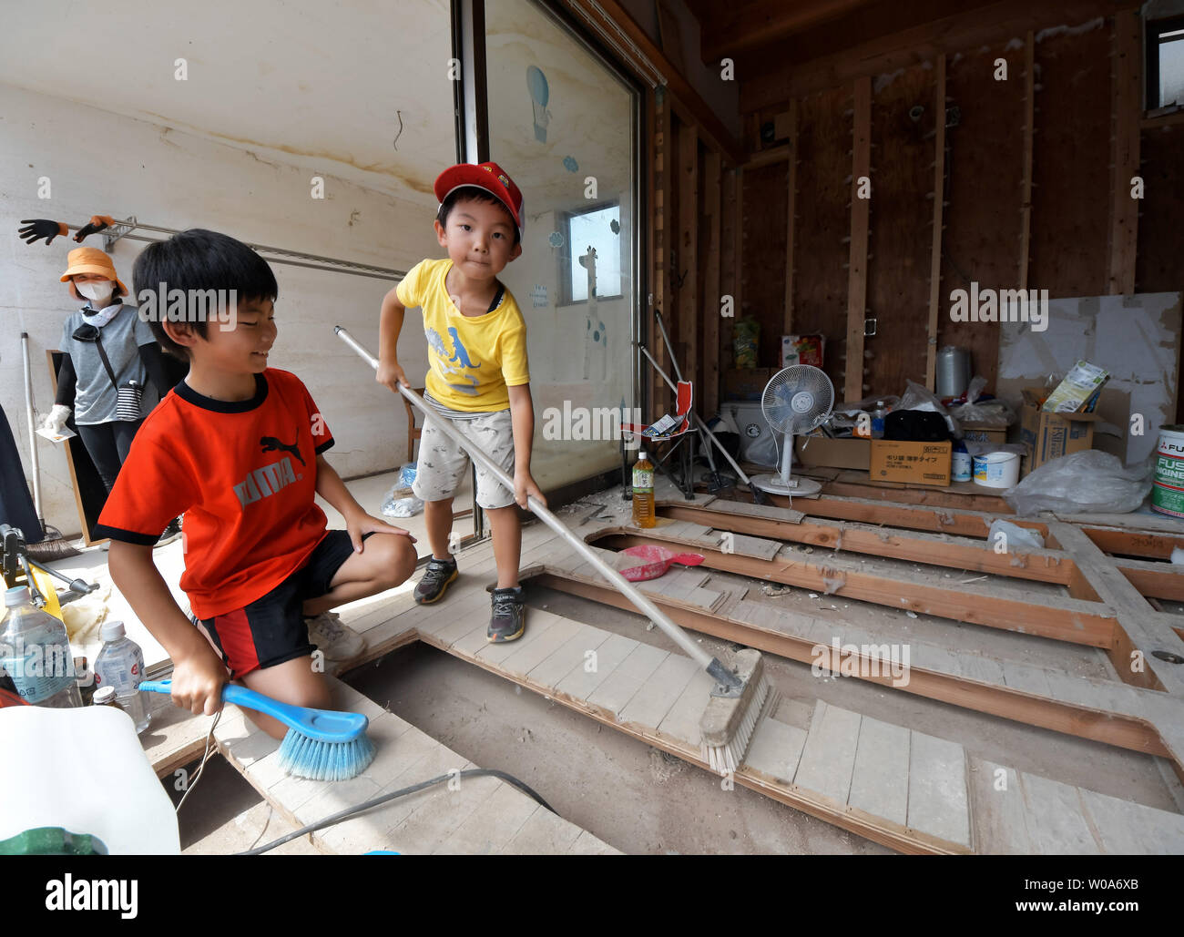 Boys clean up at a house of residents affected by flooding in Mabi Town ...