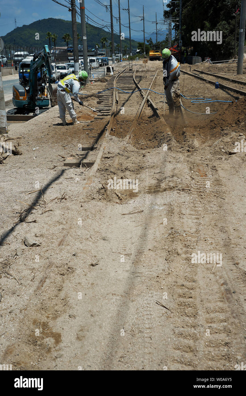 Workers repair the railway covered with mud at the Mizushiri station in ...