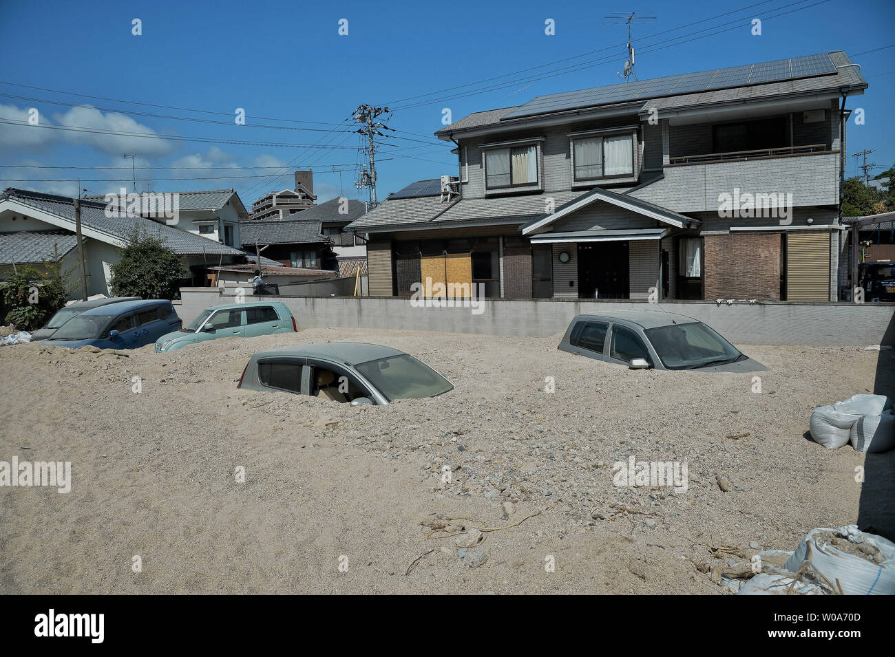 Cars and houses covered with mud are seen after heavy rains and ...