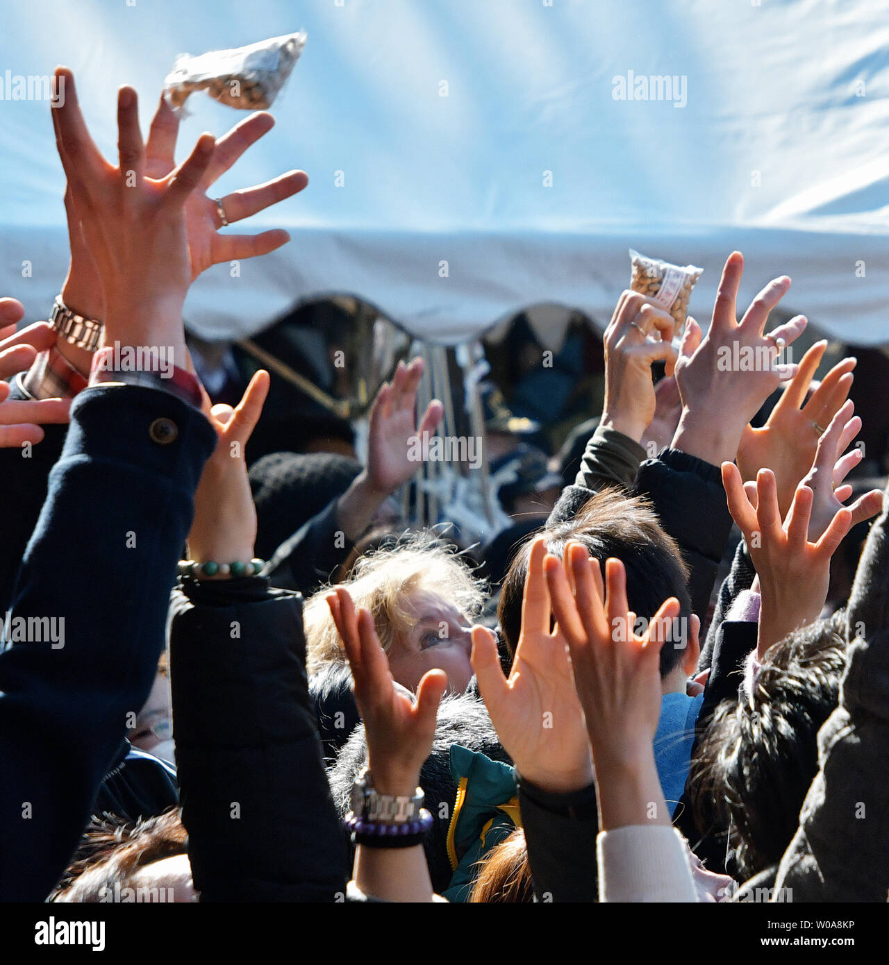 People try to catch bags containing lucky beans during the bean ...
