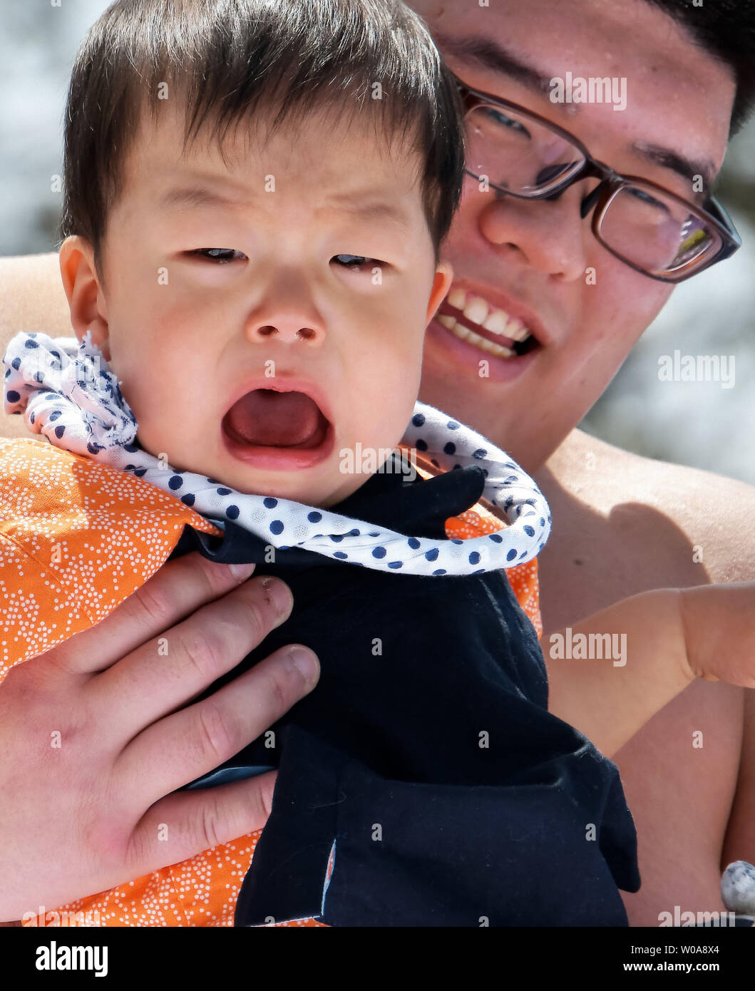 A baby held by an amateur sumo wrestler cries during the "baby crying ...