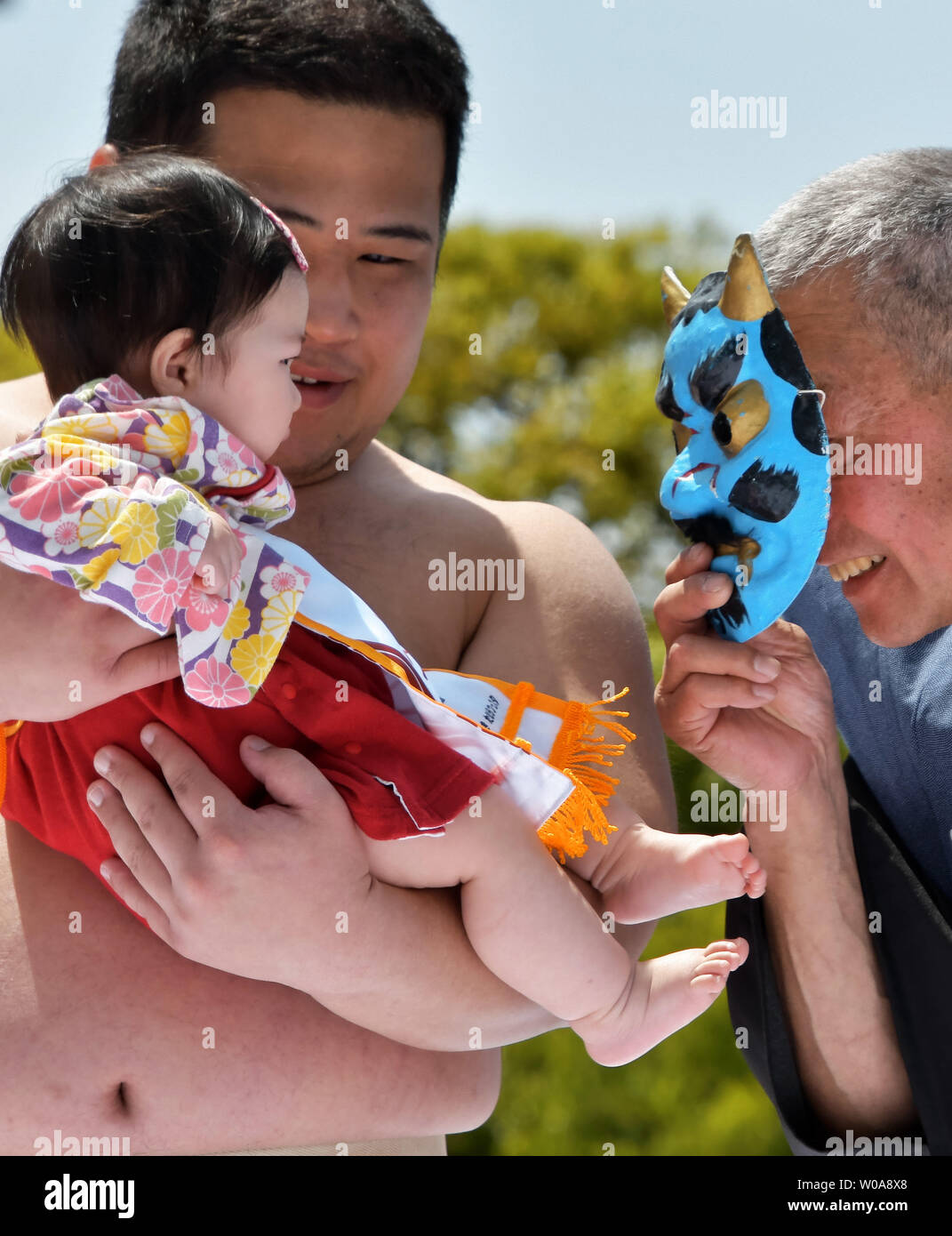 A baby doesn't cry in the arms of an amateur sumo wrestler during the ...