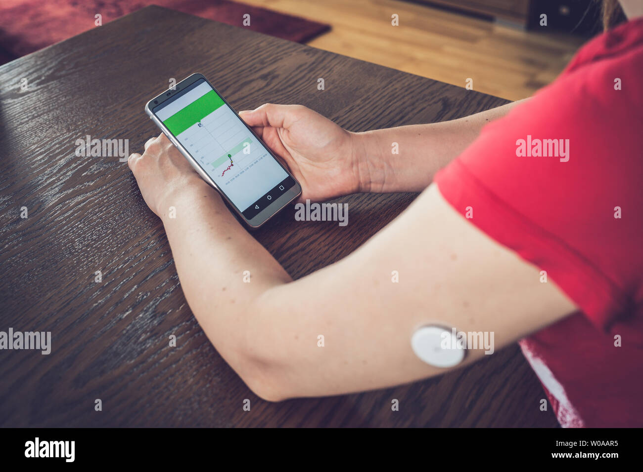 Woman checking glucose level with a remote sensor and mobile phone, new ...