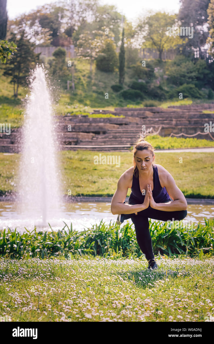 vertical photo of a young sports woman doing meditation yoga balancing ...