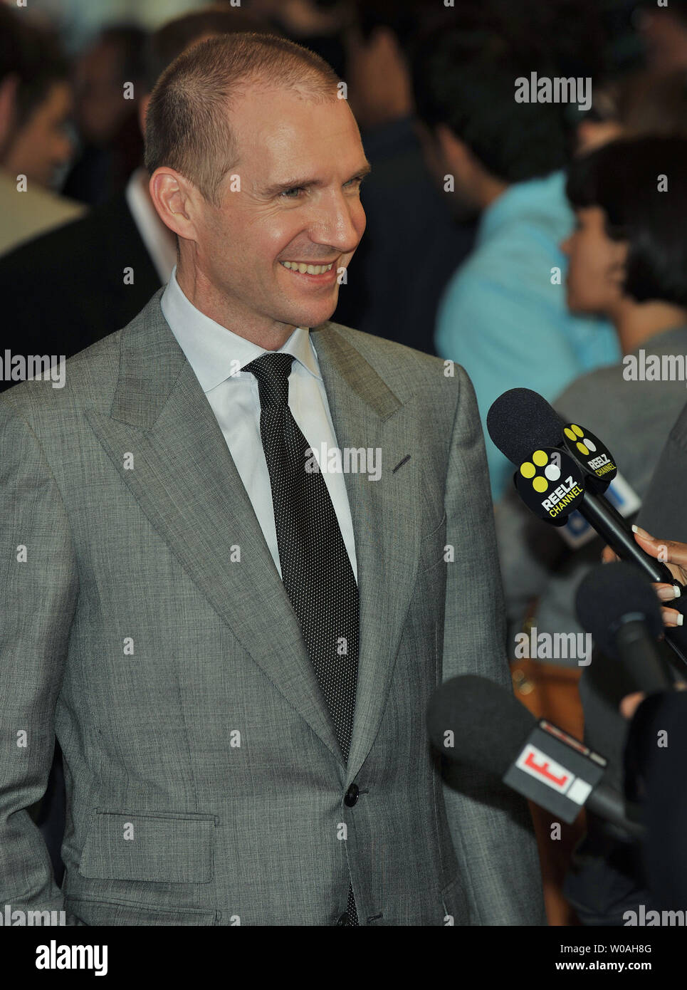 Ralph Fiennes speaks to television reporters on the red carpet as he ...
