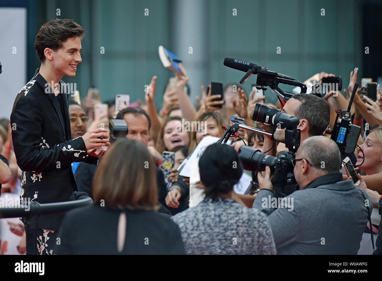 Timothee Chalamet (L) is greeted by a crush of fans and media as he ...