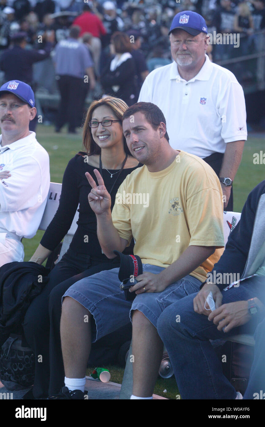 Adam Sandler poses for a picture with a fan on the Raiders bench prior ...