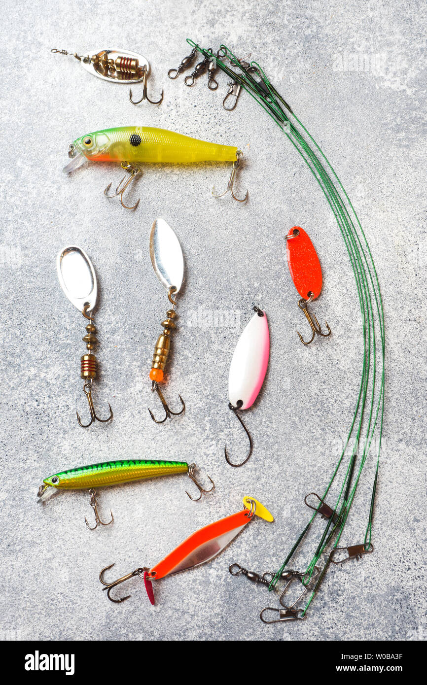 Fishing hooks and baits in a set for catching different fish on a grey ...