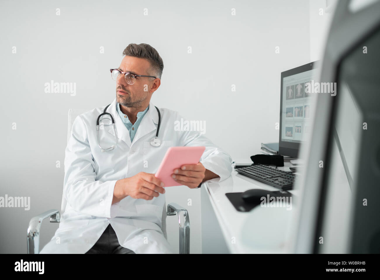 Bearded handsome plastic surgeon sitting in his modern clinic Stock ...